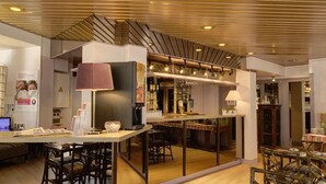 Uma área de bar moderna com teto de madeira, banquetas e um balcão com vitrine de vidro.