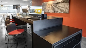 Uma área de recepção moderna com um computador, cadeiras e uma grande pintura na parede.