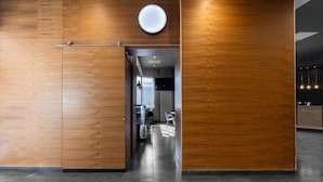 Interior moderno com painéis de madeira, um espelho redondo e um espaço de bar com banquetas.
