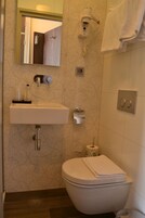 Casa de banho com lavatório, sanita, secador de cabelo e toalheiro.