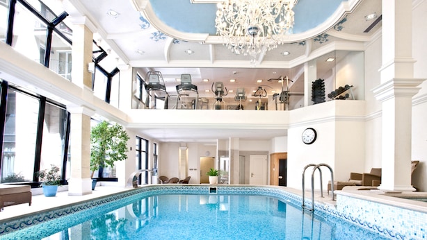 Uma grande piscina interior com vista clara para o teto, um candelabro e um relógio na parede.