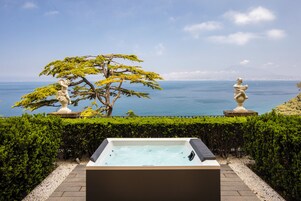 Uma banheira de hidromassagem com vista para o mar e duas estátuas.