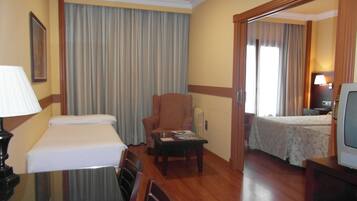 Quarto de hotel com uma cama, uma cadeira, uma mesa, um abajur e uma televisão.