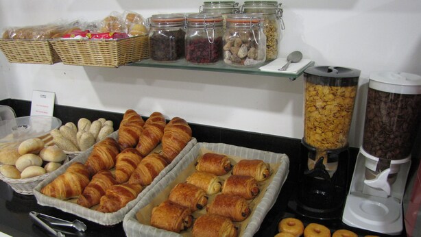 Um buffet com diversos produtos de panificação, incluindo croissants, donuts e doces.