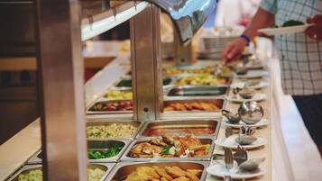 Uma mesa de buffet com diversas opções de comida e utensílios para servir.