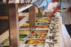 Uma mesa de buffet com diversas opções de comida e utensílios para servir.