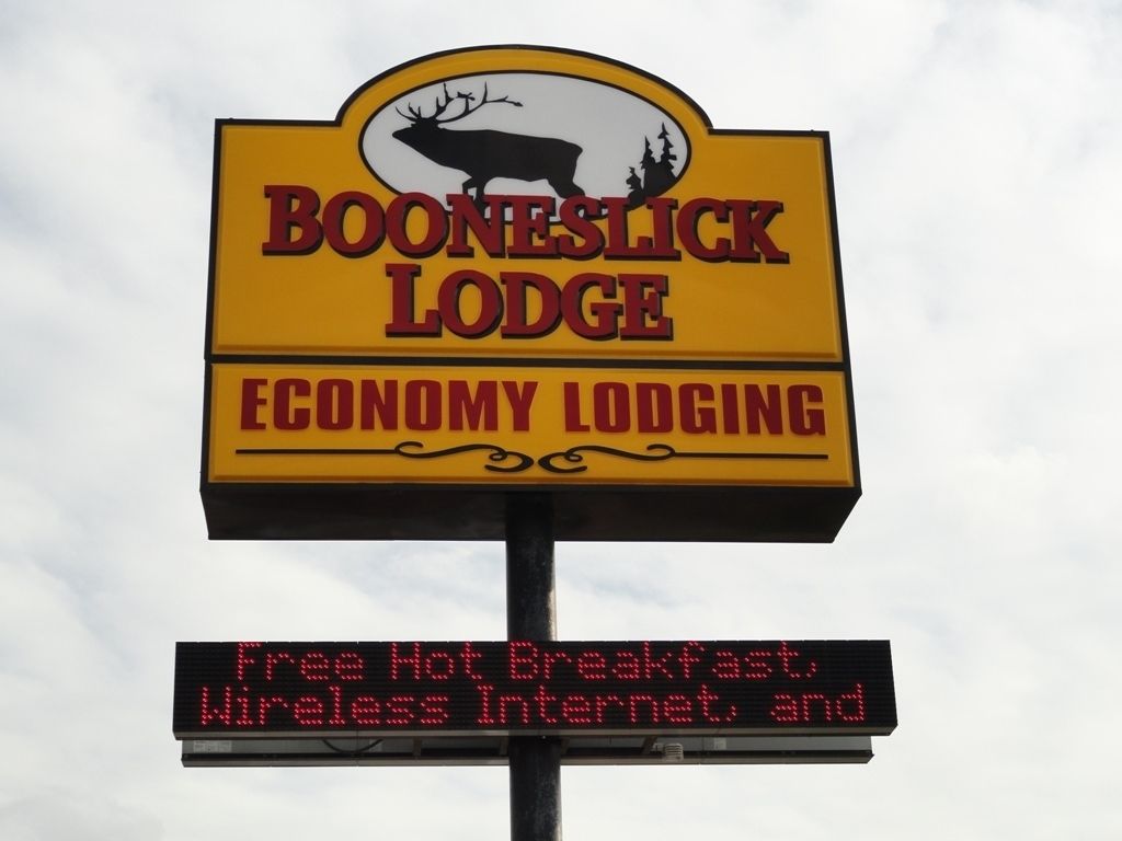Placa para Booneslick Lodge, destacando comodidades como café da manhã quente gratuito, internet sem fio e hospedagem econômica.