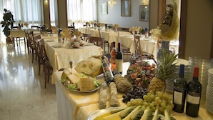 Disposição de buffet com diversos alimentos e garrafas de vinho.