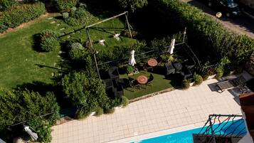 Vista aérea de uma área de piscina no terraço, com balanço, assentos e um pequeno jardim.