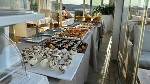 Buffet montado com diversos alimentos e vista para o exterior.