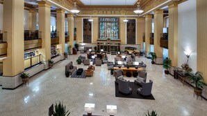 Um hall amplo com tetos altos, colunas imponentes e um vitral central.