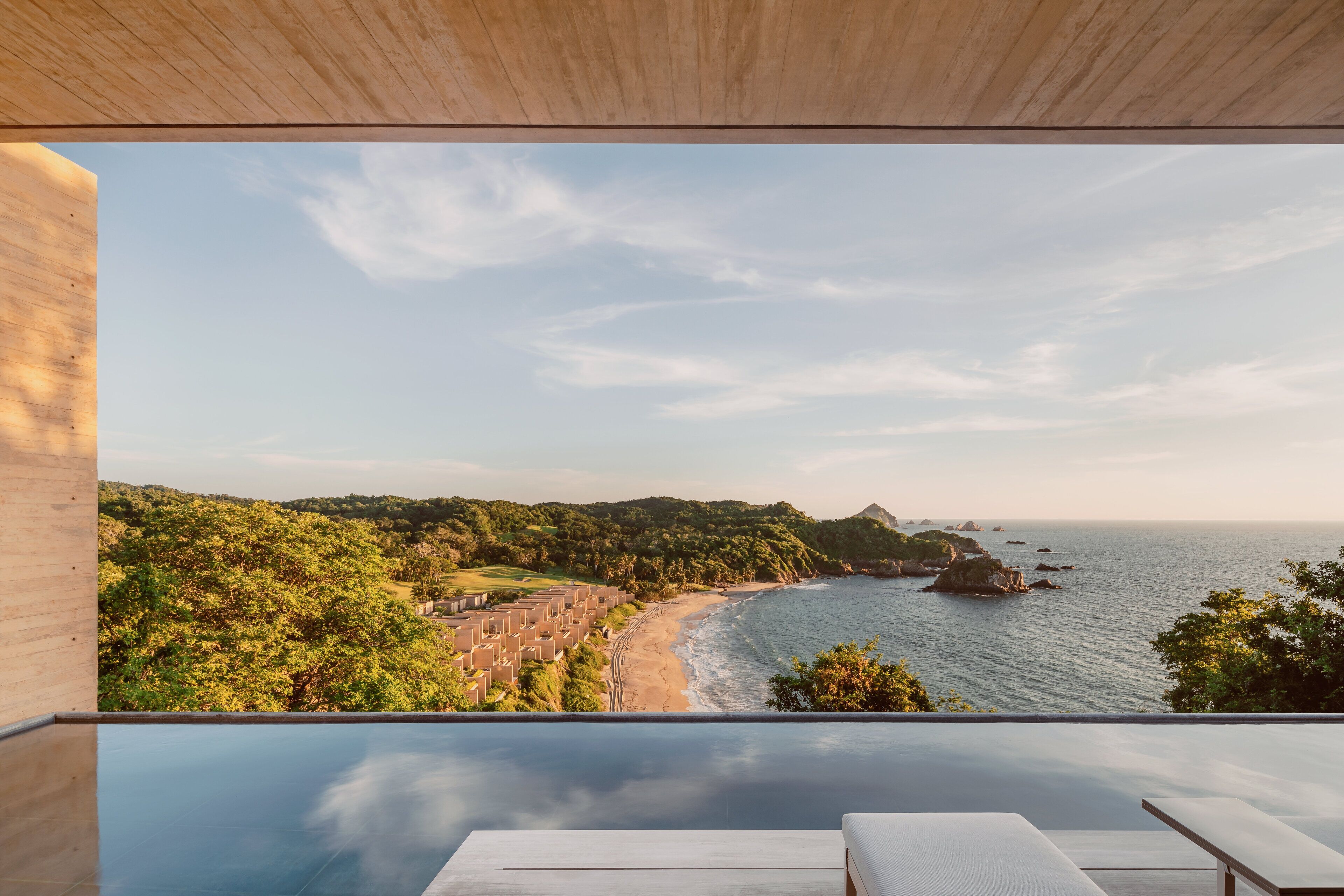 Quarto de hotel moderno com varanda e vista para a praia e oceano.
