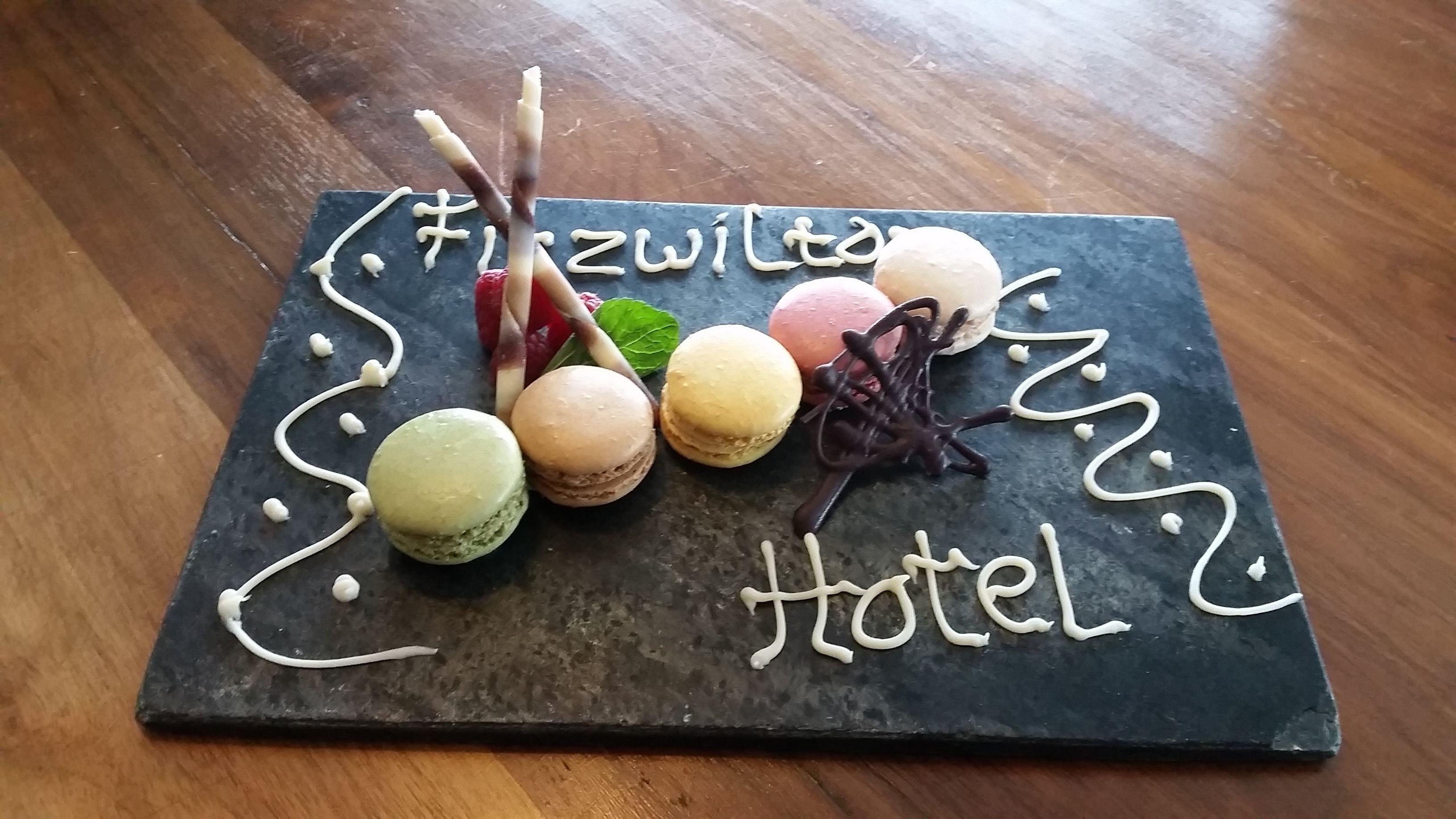 Quadro de ardósia com macarons e elementos decorativos, incluindo um letreiro que diz 'Hotel'.