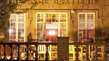 Um edifício com uma placa indicando "THE RYDE BRASSERIE" à noite.