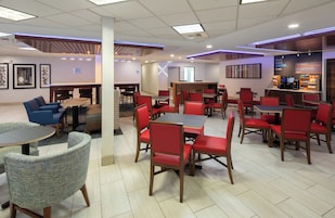 Um restaurante moderno com várias áreas de estar, incluindo mesas redondas e cabines, e um espaço para café.