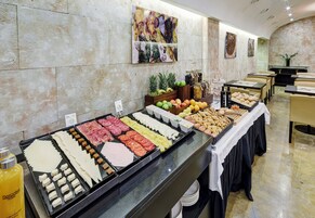 Buffet com diversas opções de comida, incluindo carnes, queijos, frutas e vegetais.