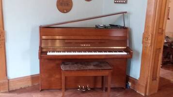 Um piano vertical Yamaha num quarto com paredes azul-claras e soalho de madeira.