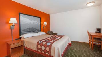 Quarto de hotel com uma cama, duas luminárias de cabeceira, uma escrivaninha e uma cadeira.