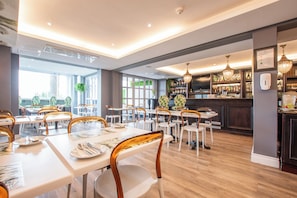 Um restaurante com várias mesas, cadeiras e um espaço de bar.