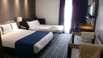Quarto de hotel com duas camas, uma escrivaninha, uma cadeira, um espelho e uma televisão.