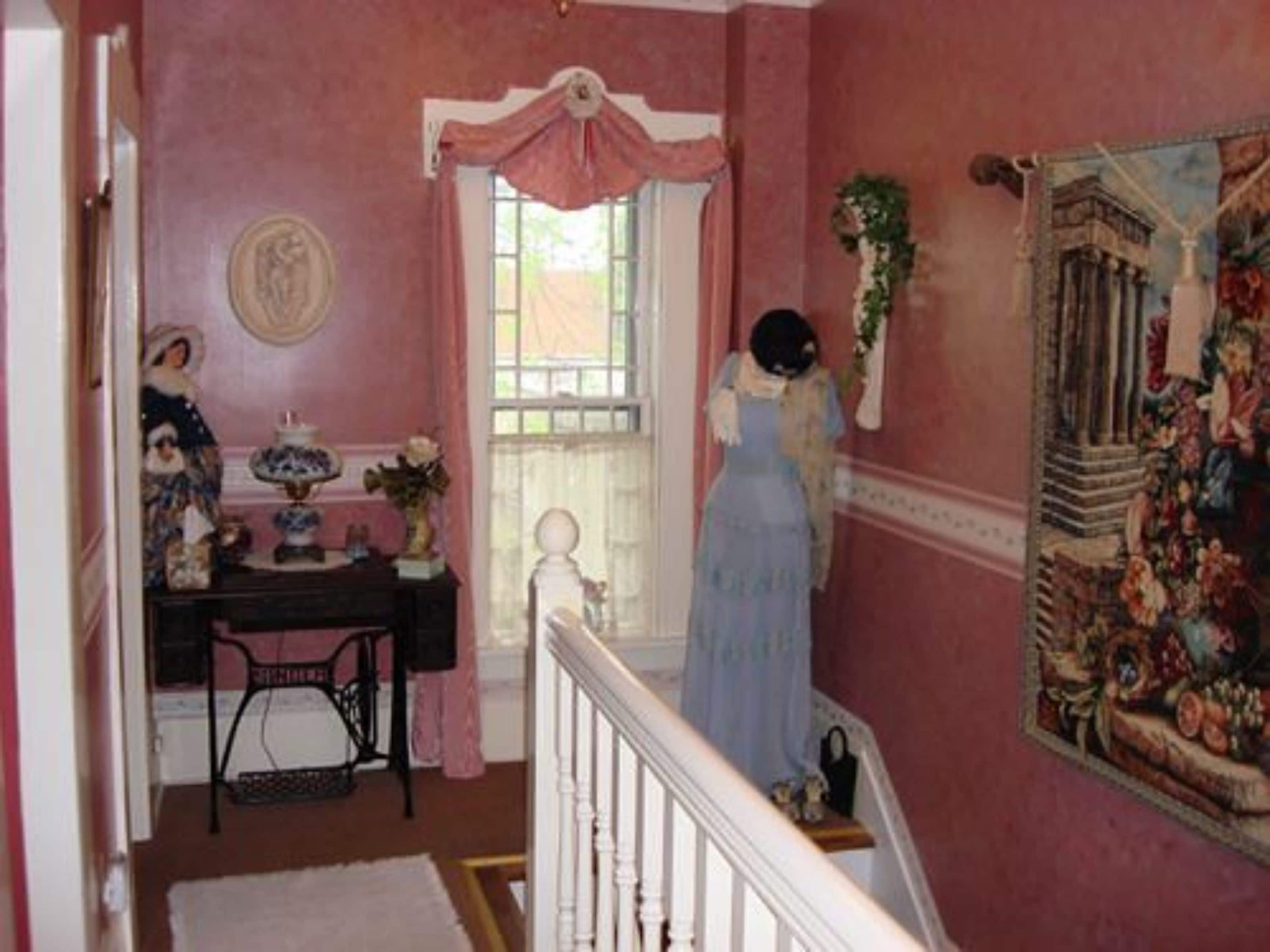 Um quarto com escada, uma mesa com cadeira e um quadro grande na parede.