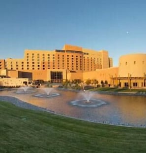Um grande hotel com vários andares, um pátio central com fontes e céu claro.