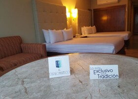 Quarto de hotel com uma cama, um sofá e dois cartazes na mesa.