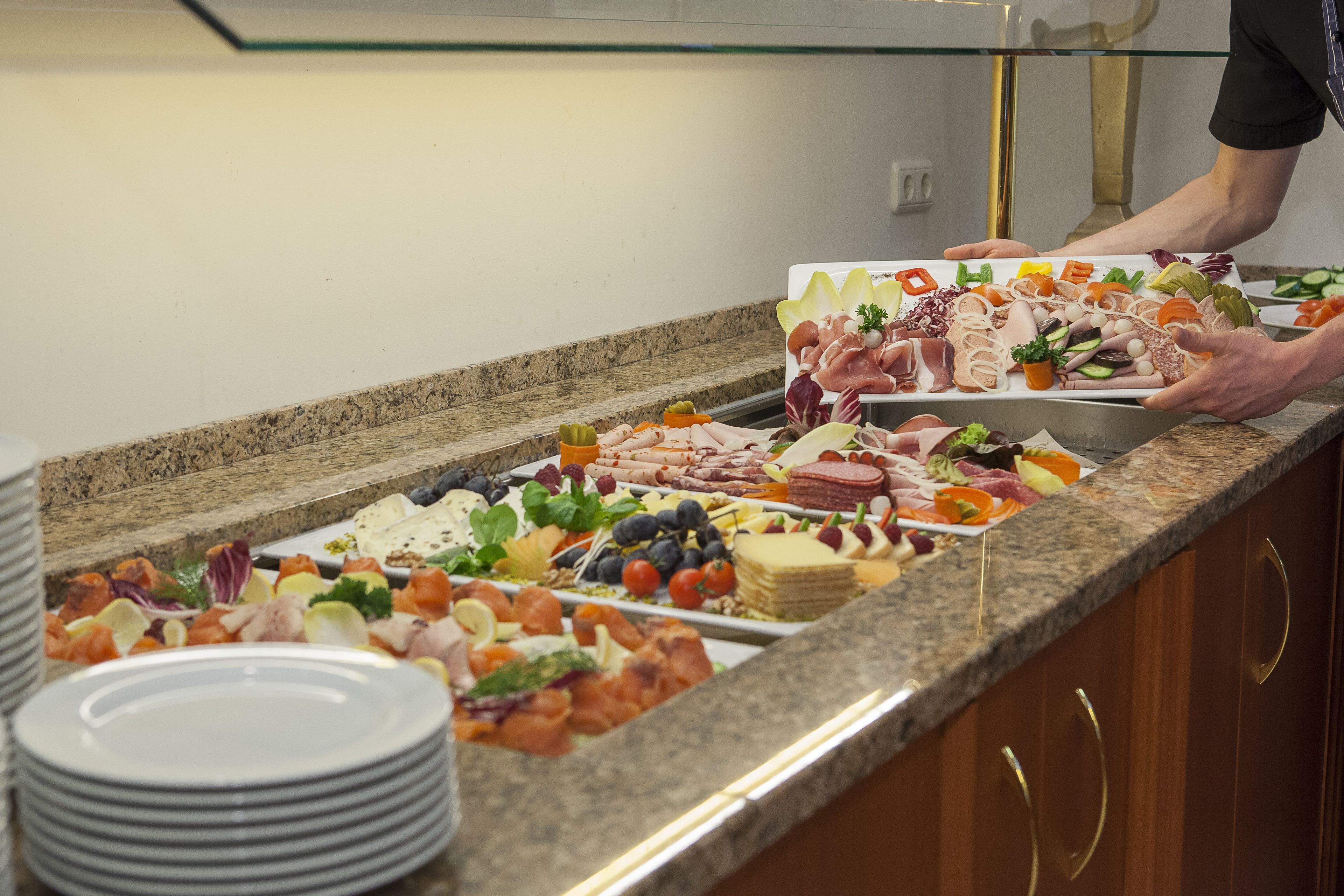 Buffet com diversos alimentos e um atendente.