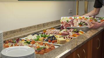 Buffet com diversos alimentos e um atendente.