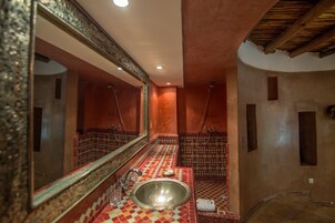 Uma casa de banho com um espelho grande, lavatório e chuveiro.