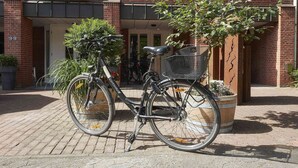 Uma bicicleta estacionada em frente a um edifício com fachada de tijolos, uma porta e uma janela.