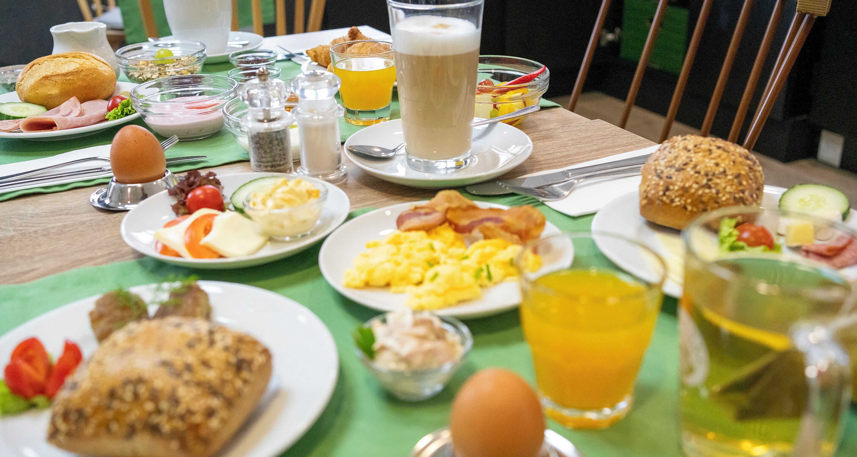 Uma mesa de café da manhã com diversos pratos, incluindo ovos, torradas e frutas.
