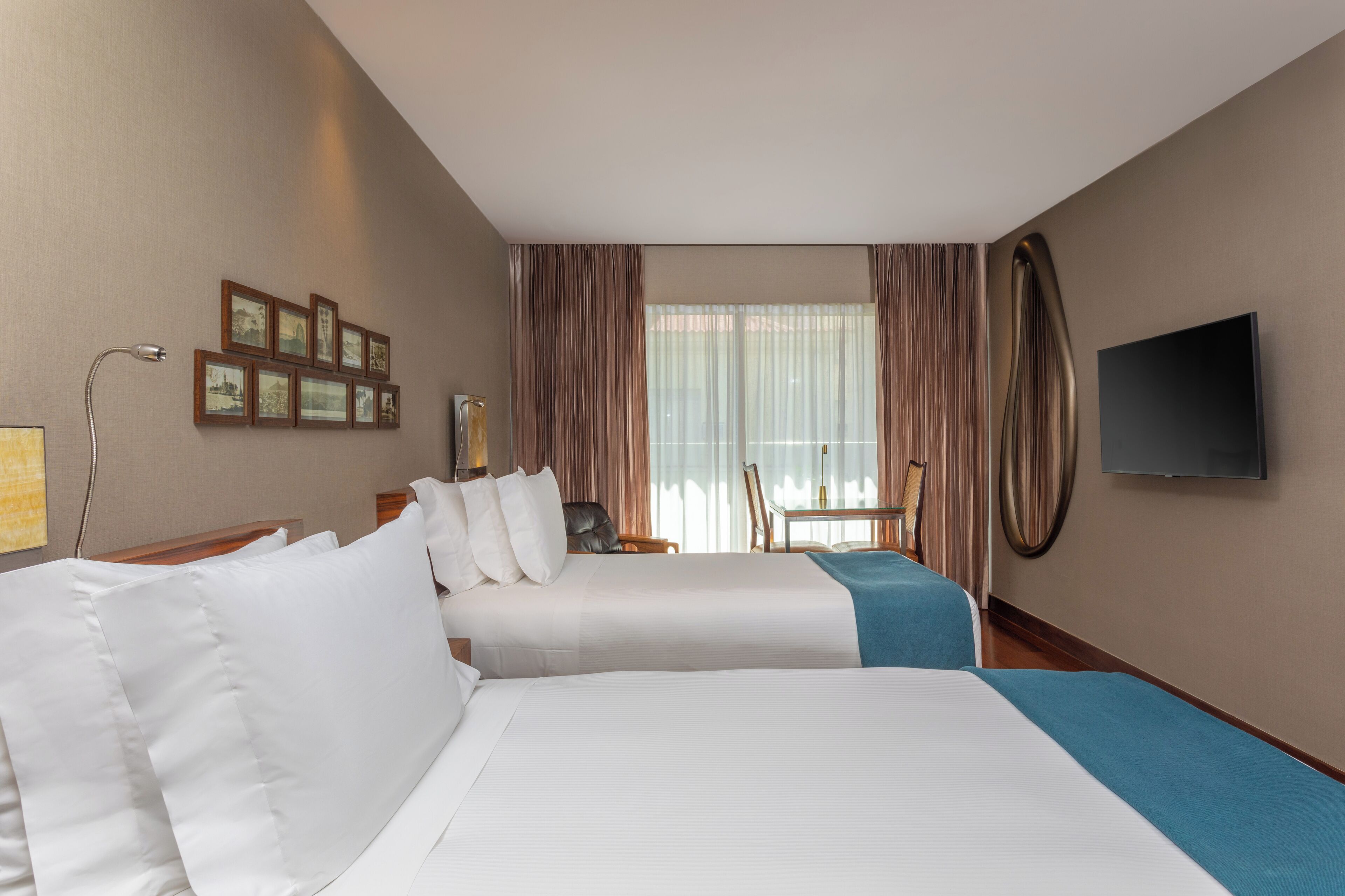 Quarto de hotel com duas camas, uma TV de tela plana, uma escrivaninha e uma cadeira.