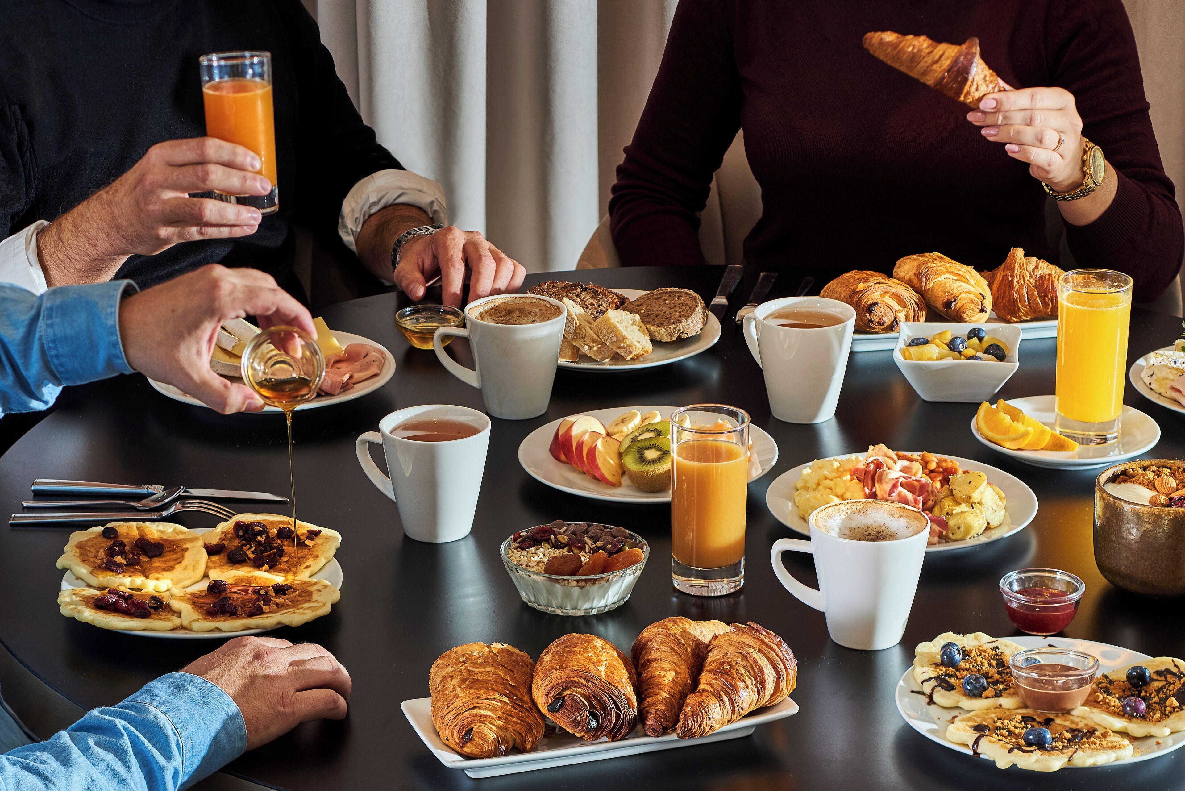 Uma mesa posta para o café da manhã, com diversos alimentos e bebidas.