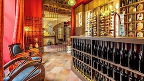 Uma área de bar com prateleiras de garrafas de vinho, uma escadaria e cadeiras de madeira.