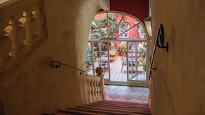 Escadaria que leva a um pátio com parede vermelha e plantas em vasos.