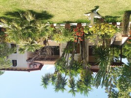 Um edifício com telhado em telhas, cercado por palmeiras e flores vermelhas.