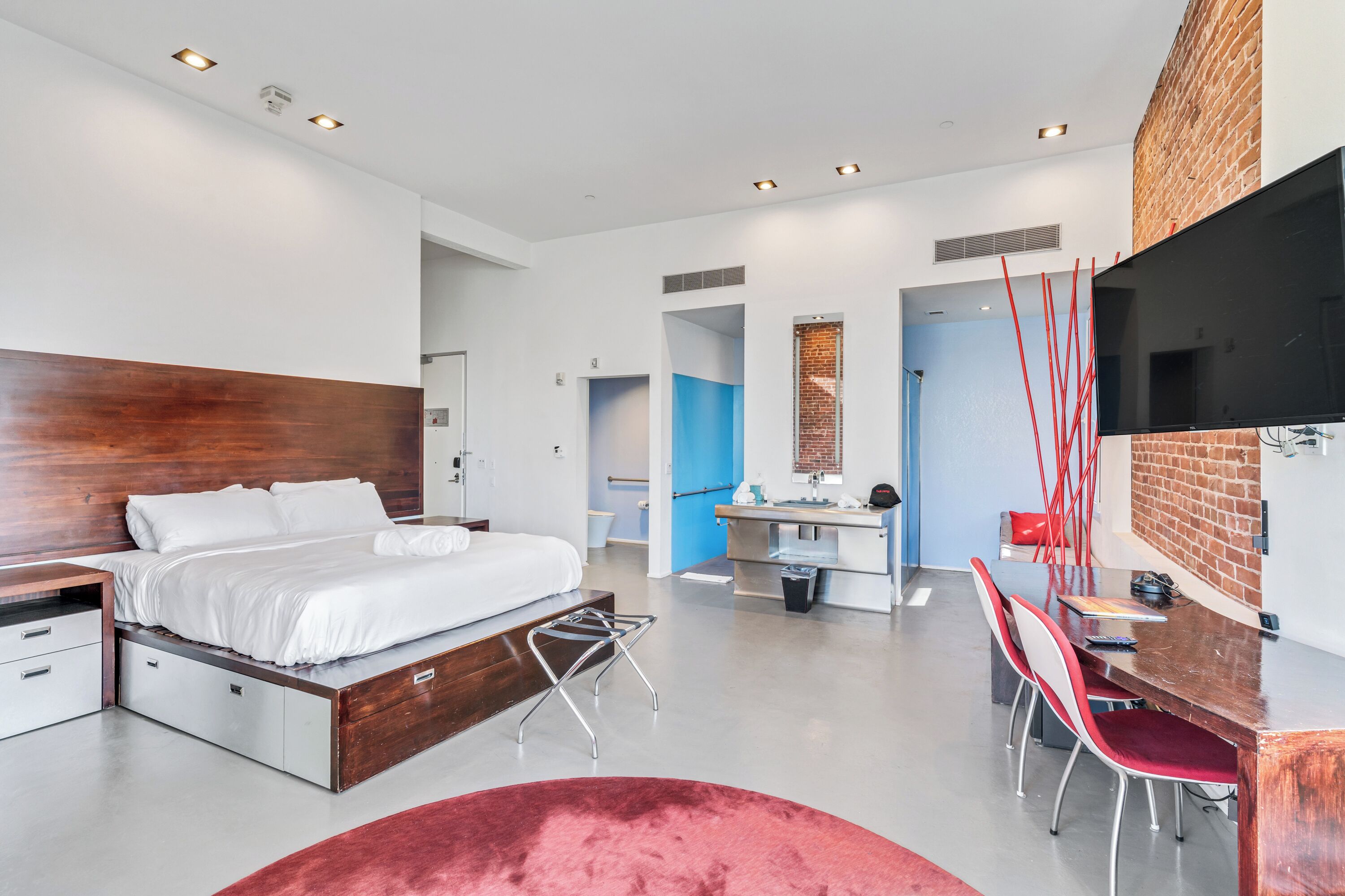 Quarto de hotel moderno com cama, escrivaninha e televisão.