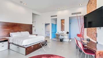 Quarto de hotel moderno com cama, escrivaninha e televisão.