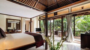 Quarto espaçoso com uma cama grande, televisão e varanda com vista para vegetação exuberante.