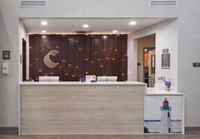 Balcão de recepção com design em painel de madeira, dois laptops HP e uma placa indicando área exclusiva para funcionários.