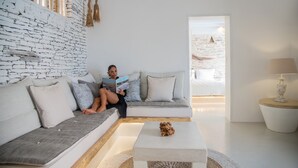 Uma sala de estar moderna com parede de tijolos brancos, um sofá cinza e uma mesa de centro branca.