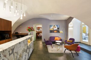 Um interior moderno com bancada de mármore, assentos roxos e uma área de refeições.