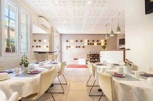 Espaço de refeições de hotel com mesas preparadas para o serviço, um tapete vermelho e um design de teto moderno.