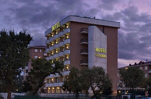 Um hotel com vários andares, varandas, um letreiro grande com a palavra 'HOTEL' e um letreiro com 'VITERO'.