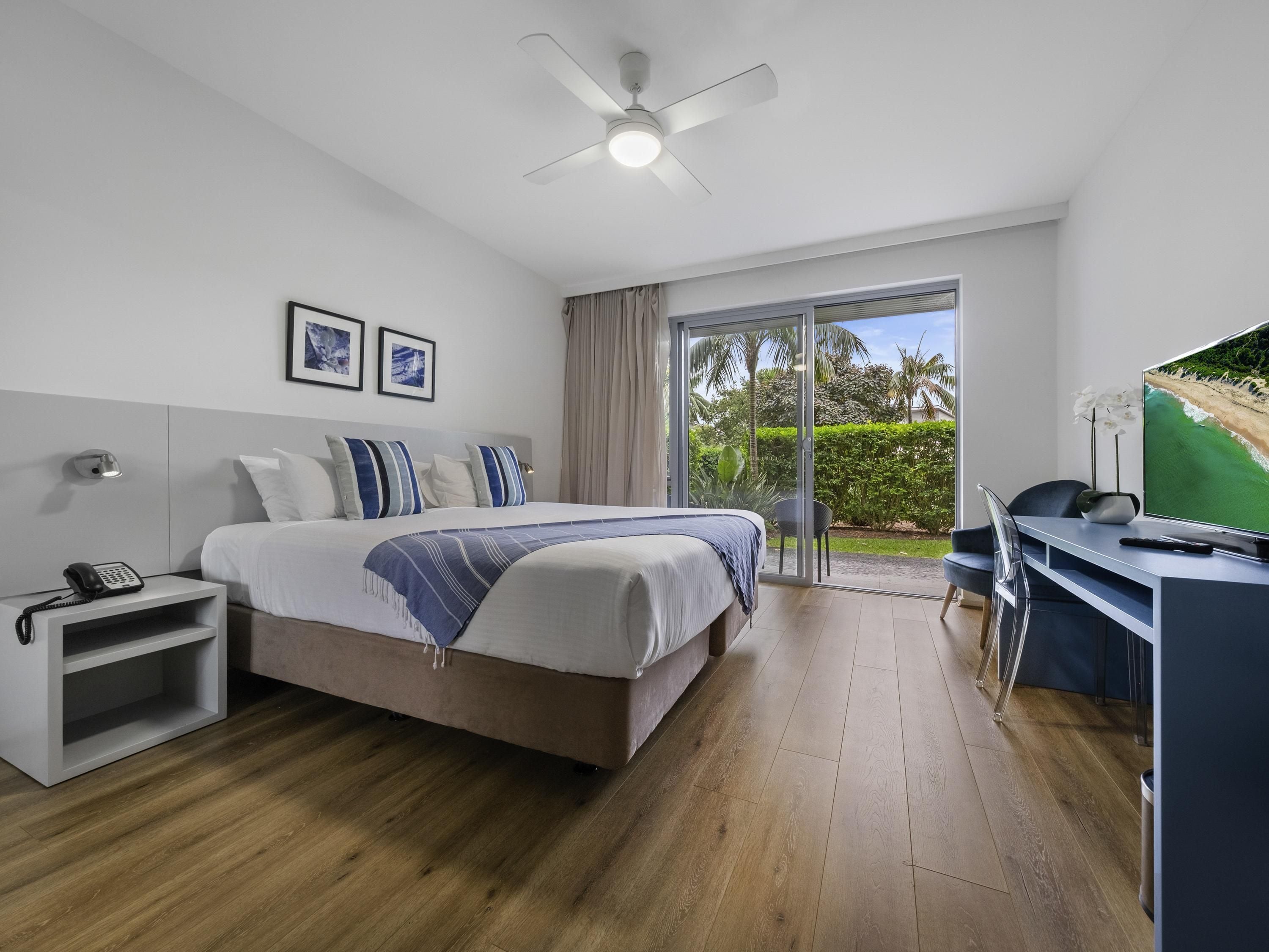 Quarto de hotel moderno com cama, escrivaninha e uma grande janela com vista para o exterior.
