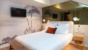 Quarto moderno com uma cama grande, um banco, uma TV e um espelho.