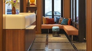 Um interior moderno com área de estar, balcão de recepção em madeira e grandes janelas.