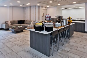Uma cozinha moderna com uma ilha central, banquetas de bar e uma área de refeições com sofá.