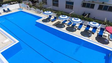 Piscina no terraço com água azul, rodeada por espreguiçadeiras e guarda-sóis.